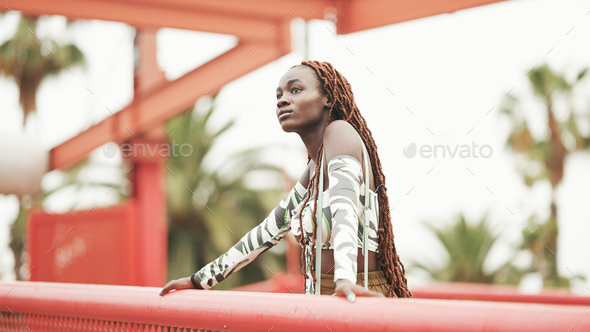 Gorgeous woman with African braids wearing top stands on the bridge ...