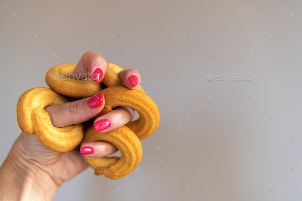 butter cookie rings on the fingers of a woman's hand on a gray ...