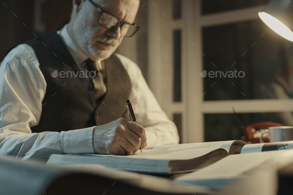 Academic professor writing down notes and reading a book Stock Photo by ...