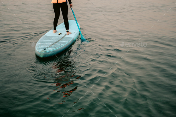Young women in thermo clothing rowing oar on sup board paddleboard ...
