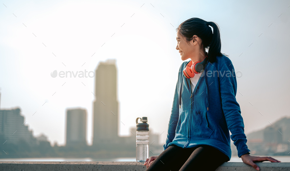 Young asian women sit to rest after jogging a morning workout in the ...