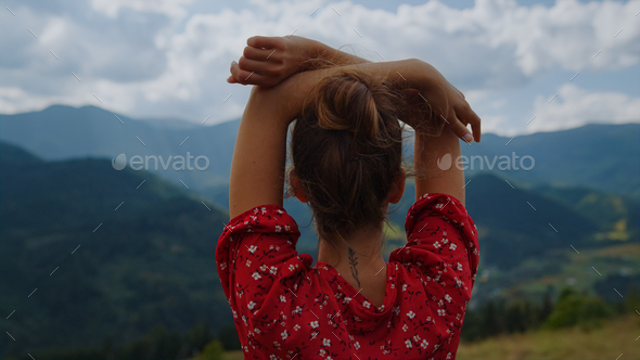 Back view woman raising hands standing in front beautiful mountains ...