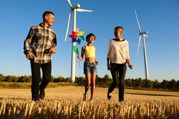 Girl playing with a wind turbine toy while having fun with her parents ...