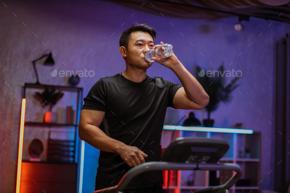 Attractive sports asian man drinking water from bottle doing fitness ...