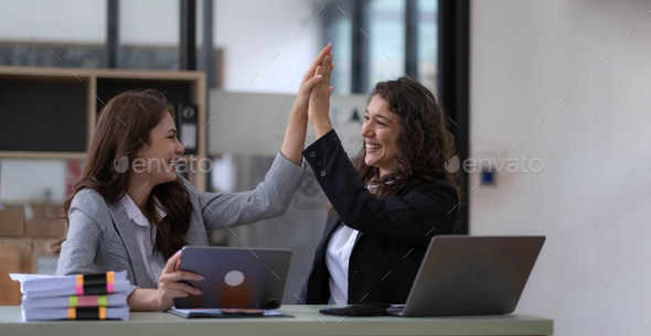 Two young Asian businesswomen show joyful expression of success at work ...