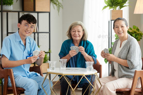 Smiling Nurse playing Cards with Patients Stock Photo by DragonImages