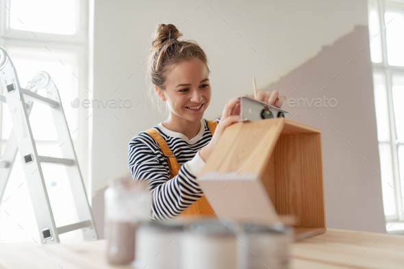Portrait of young woman remaking shelf in her new flat. Concept of ...