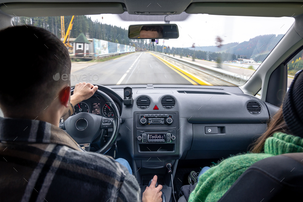 Rear back view from passenger seat of man and lady sitting inside car ...
