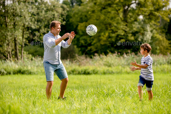 Father and daughter watching bugs in the grass using magnifying glass ...