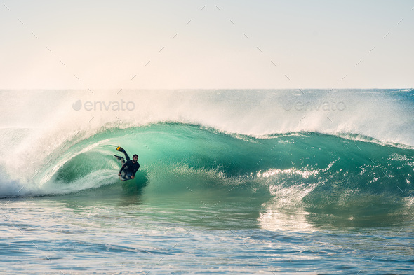 surfer riding a perfect barrel of a wave at sunset Stock Photo by Raul ...