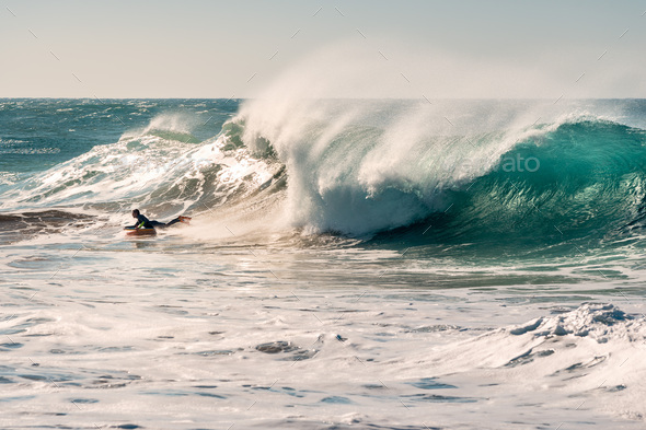 surfer riding huge wave that chases him at sunset Stock Photo by Raul ...