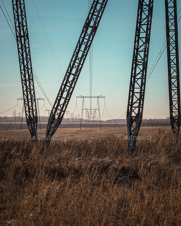 high-voltage power lines poles at sunset in the field, high voltage ...