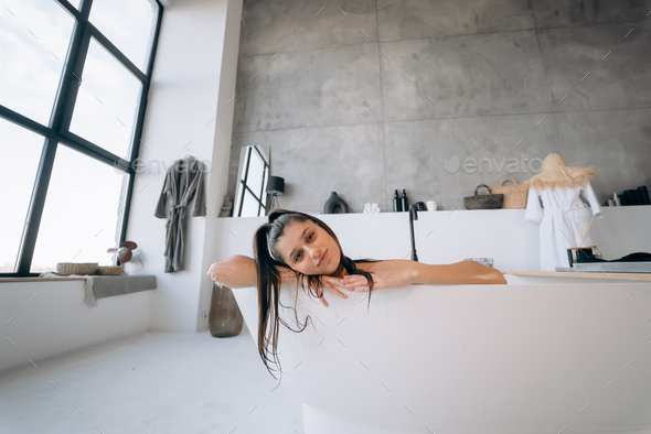 Relaxed lady taking bath, enjoying and relaxing while lying in bathtub ...