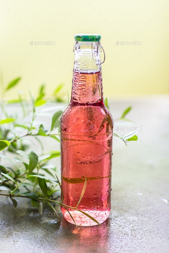 Cold pink lemonade in bottle, green background. Summer refreshing drink ...