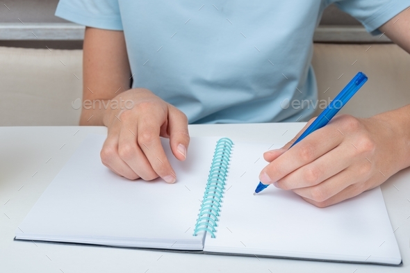 Female student hand holding a pen writing in a notebook. Business woman ...