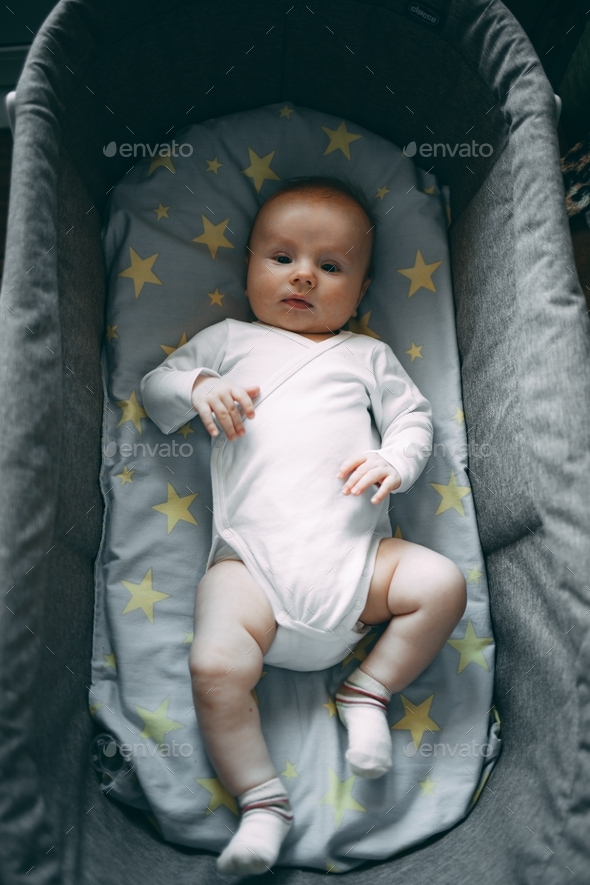 The baby woke up and lies in the crib, top view Stock Photo by photability