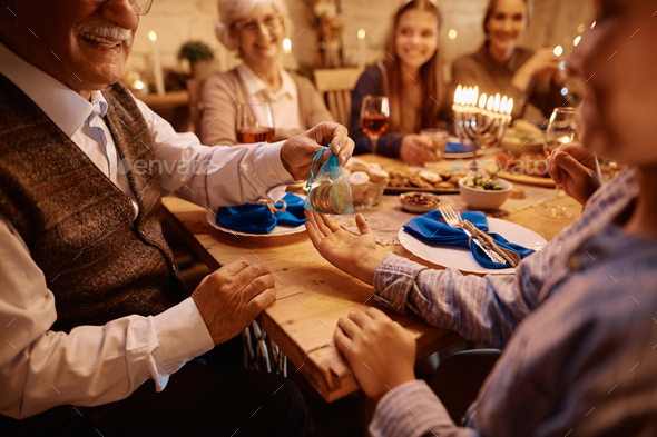 Senior man giving Hanukkah gelt to his grandson while celebrating ...