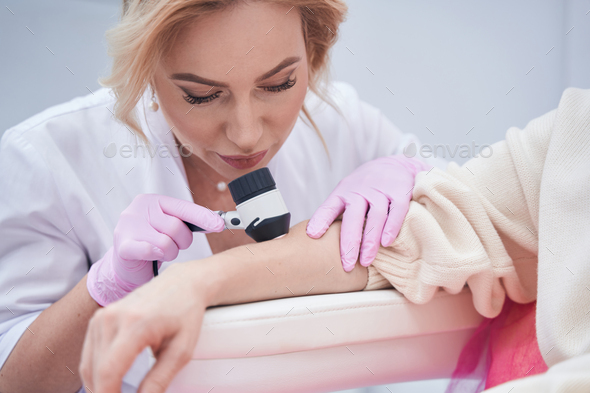 Focused doctor checking patient skin with dermatoscope Stock Photo by ...