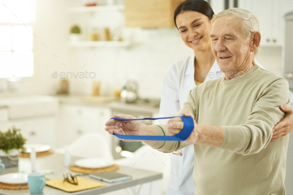 Smiling senior citizen using fitness rubber band in his hands during ...