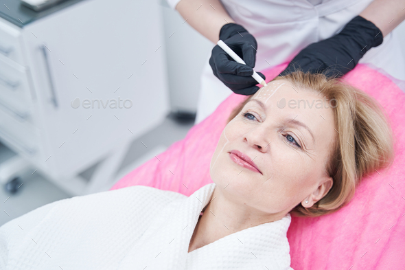 Beautician drawing line on woman face in beauty salon Stock Photo by ...