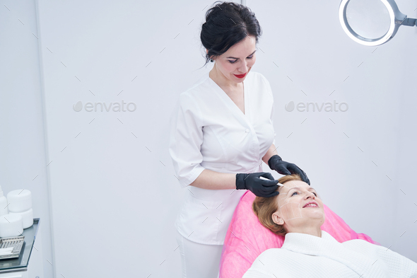 Cosmetologist drawing line on woman face in beauty salon Stock Photo by ...