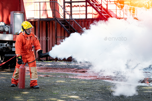 Fireman wearing firefighting suite using fire extinguisher fighting ...
