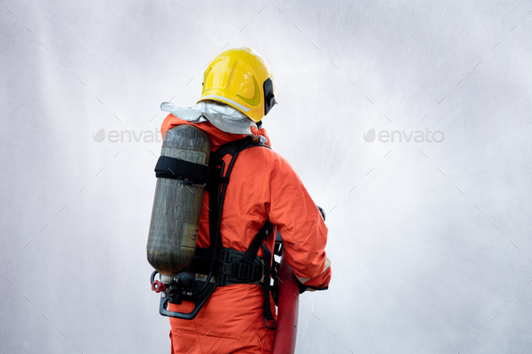 Fireman wearing firefighting suite using fire extinguisher fighting ...