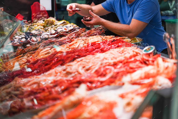 Fishmonger selling fish inside seafood market - Focus on right hand ...