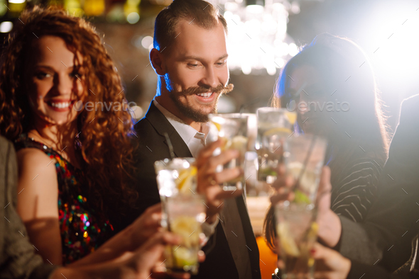 Cheering and drinking cocktails. Group of friends partying in a ...