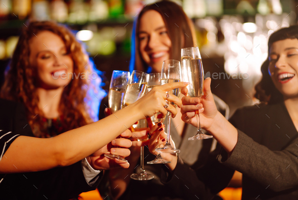 Cheering and drinking cocktails. Group of friends partying in a ...