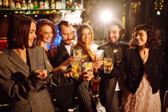 Cheering and drinking cocktails. Group of friends partying in a ...