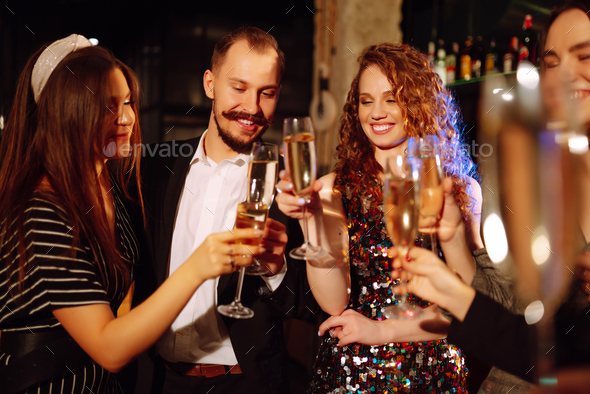 Cheering and drinking cocktails. Group of friends partying in a ...