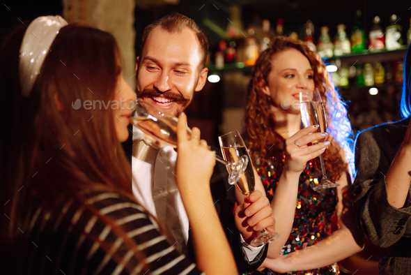 Cheering and drinking cocktails. Group of friends partying in a ...