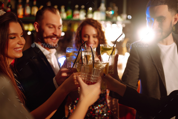 Cheering and drinking cocktails. Group of friends partying in a ...