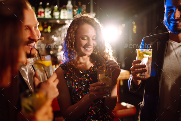 Cheering and drinking cocktails. Group of friends partying in a ...