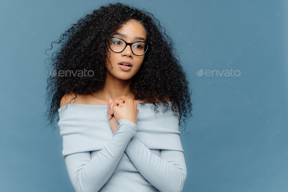 Worried nervous female keeps hands pressed together over chest, has ...
