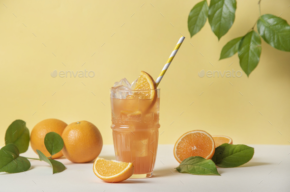 A glass of refreshing orange juice with a slice of orange and ice on a yellow background Stock ...