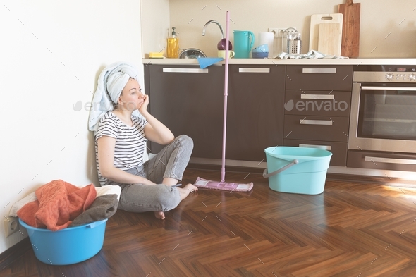 Sad young woman housewife in the kitchen to calm down. Disorder, mess ...