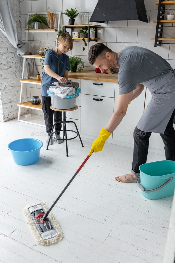 Handsome father and his teenage son keeping house clean, doing chore ...