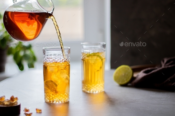 The process of pouring iced tea, near lemon and sugar. Stock Photo by ...