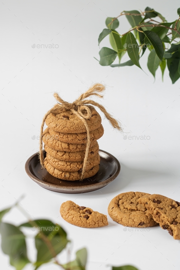 A stack of chocolate chip cookies tied with jute thread. Leaves frame ...