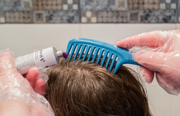 Coloring blond hair at home: gloved hands squeeze out a tube of pink ...