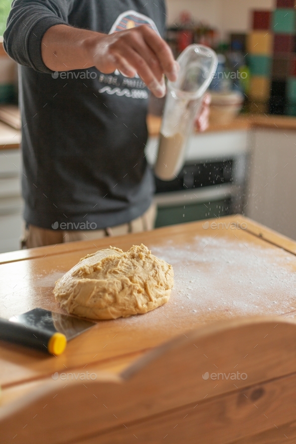 A man flours a surface to shape a brioche dough Stock Photo by StudioAour