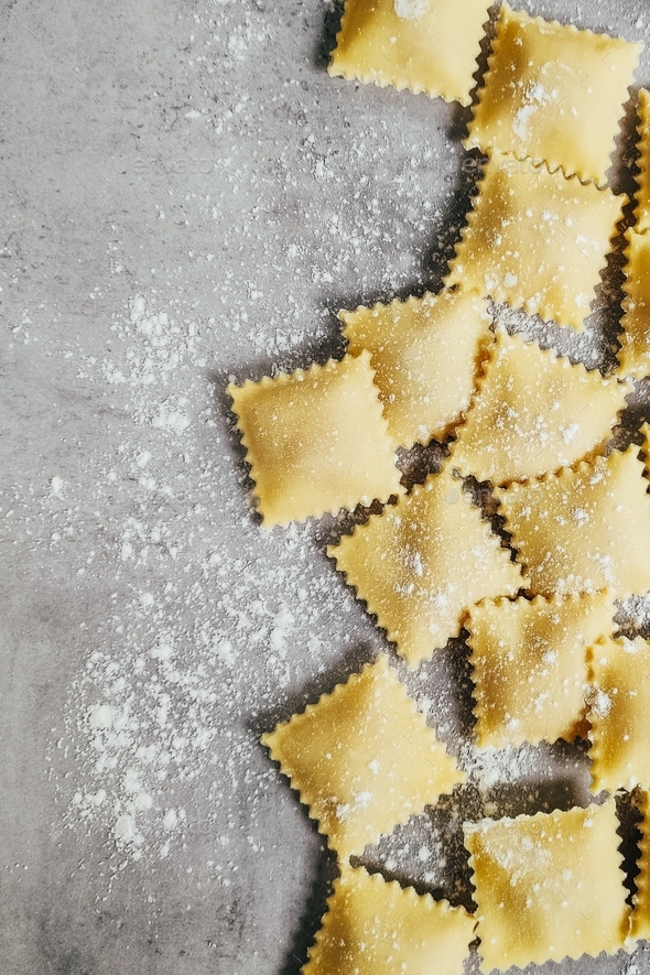 Homemade ravioli square-shape on grey floured working surface ready to ...