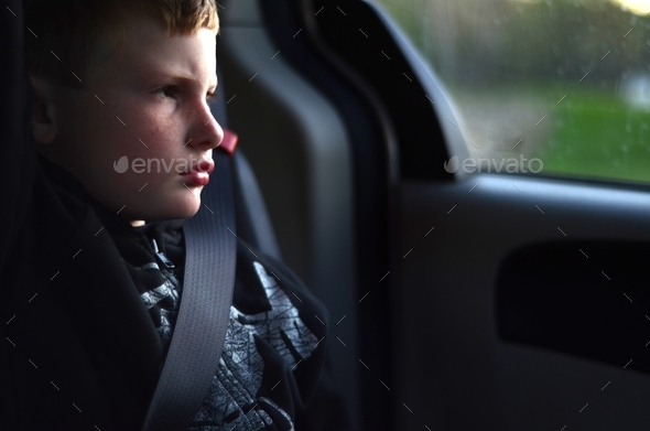 Bored on a long drive in the backseat of the car. Stock Photo by ethomander