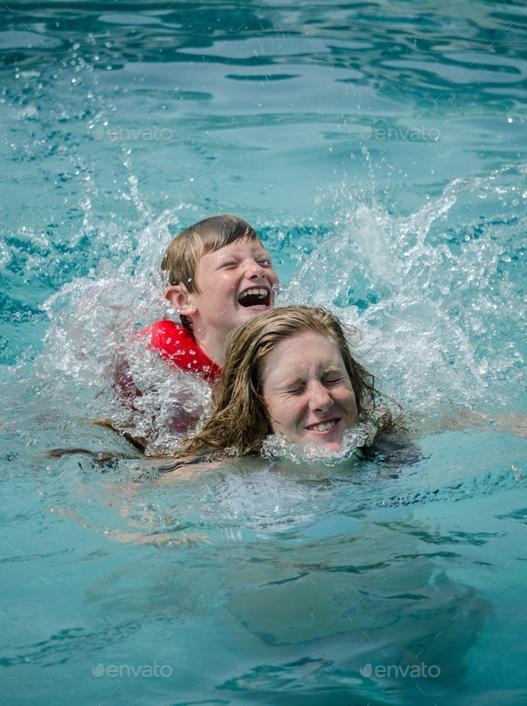 Brother and sister having fun in the pool at home Stock Photo by ethomander