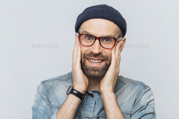 Portrait of attractive young man with thick beard and mustache looks ...