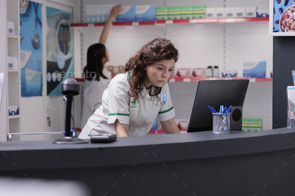 Pharmacy worker checking medication list on computer monitor Stock ...