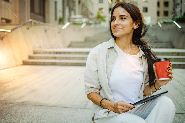 Beautiful woman going to work with coffee walking near office buildings ...