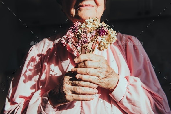 Old 80-year-old woman holds dried hydrangea and rose flowers in her ...